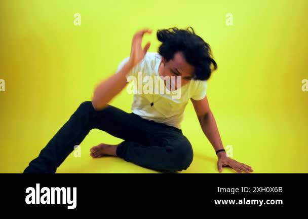 Fearful Indian man sitting on yellow background, Scared man sitting on ...