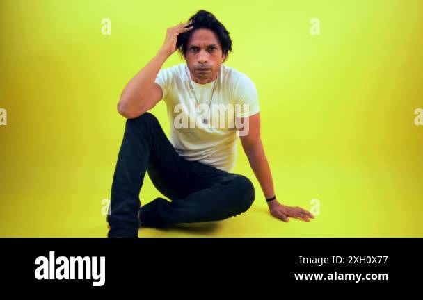 Fearful Indian man sitting on yellow background, Scared man sitting on ...