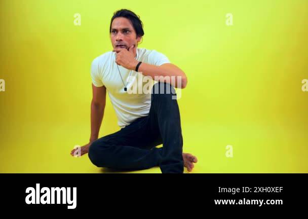 Fearful Indian man sitting on yellow background, Scared man sitting on ...