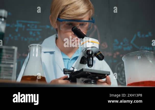 Smart boy using microscope analysis sample at science laboratory in STEM science class or ...