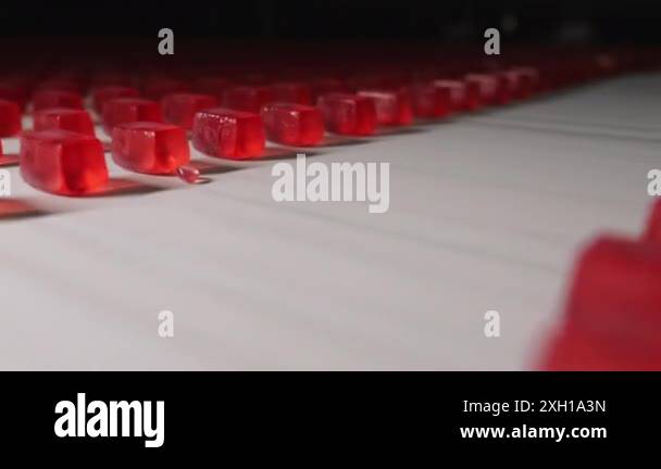 Conveyor belt in a chocolate factory. Candy production. Red jelly ...