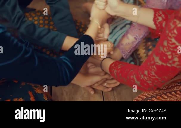 A group of people wearing traditional clothing joining hands in a ...