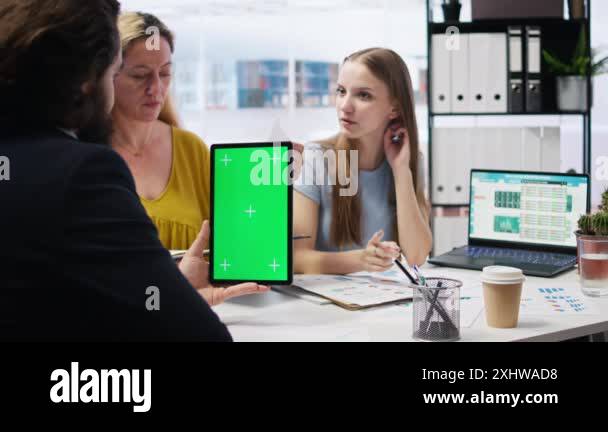 Broker holding green screen tablet, meeting with clients to provide stock exchange analysis ...