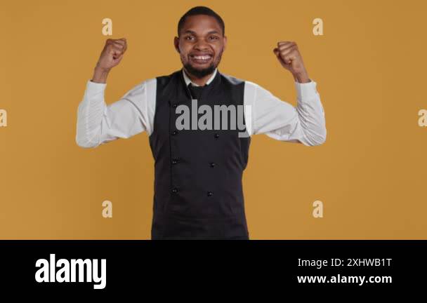 Waiter flexing his muscles and showing his strength in studio, acting ...
