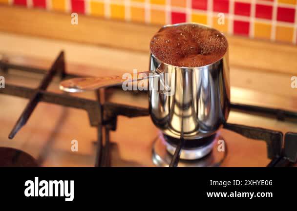 Brewing a turkish style coffee in stainless steel cezve on a gas stove ...