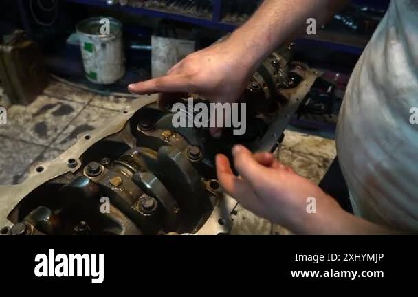 A mechanic works on a car engine, inspecting and adjusting parts. The ...