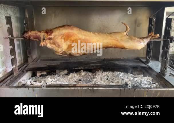 Roast lamb on a spit. Roasted lamb. Sheep on a spit above fire in a ...