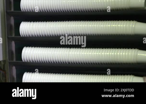 Stacks of plastic cups on a conveyor belt at plastic recycling factory ...
