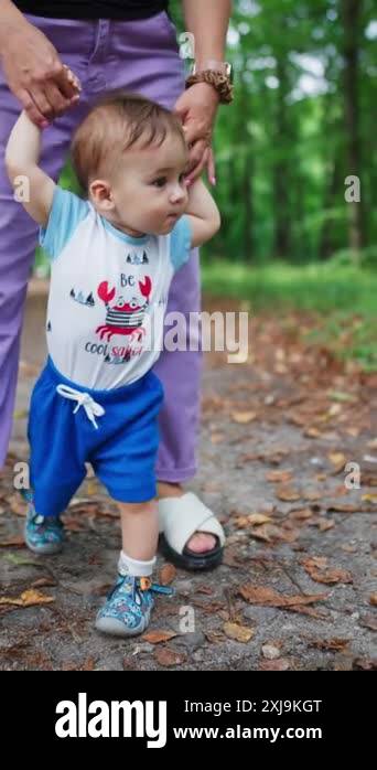 Little toddler stepping slowly looking around. Mommy's holding her baby ...