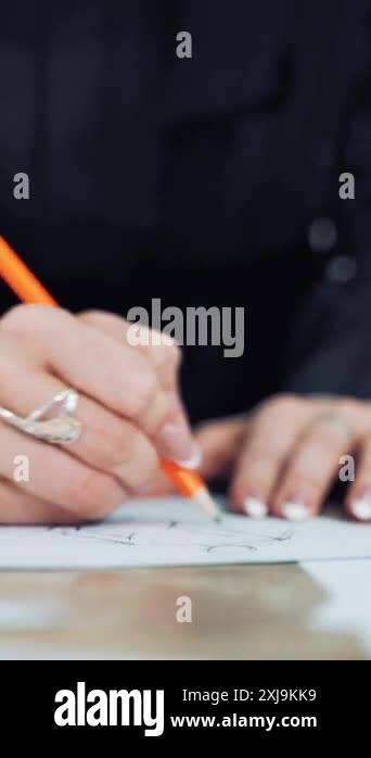 Hands of a professional tailor is drawing a sketch with a sharp pencil ...