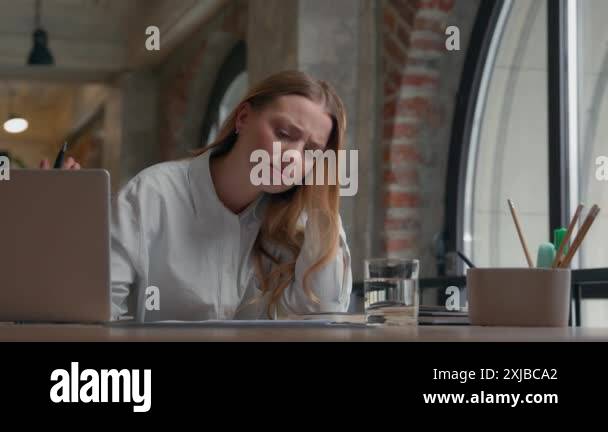 Stressed Caucasian office female worker woman student girl work reading documents writing report ...