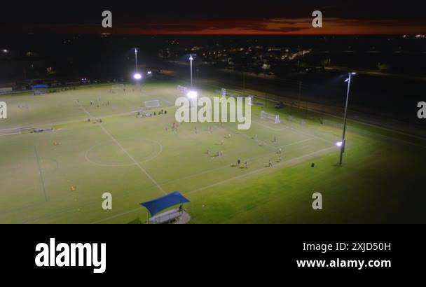 Schoolchildren playing football game on illuminated campus stadium at ...