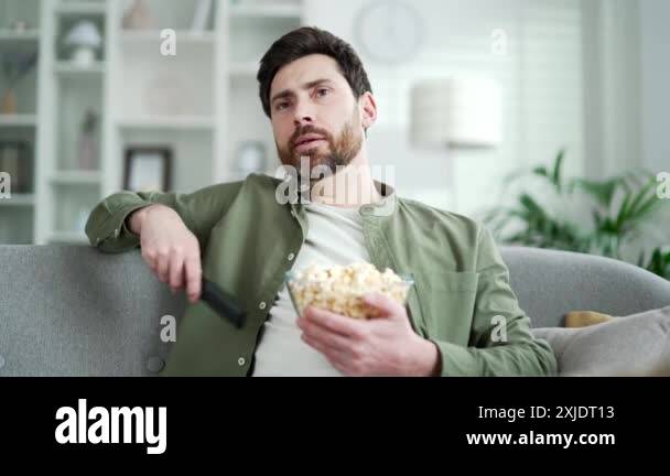 Lonely sad handsome man bored switching television channels with remote ...