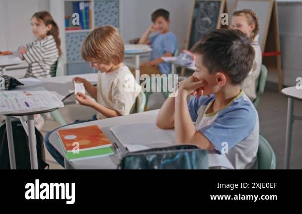 Funny child reading note from classmate laughing at class room closeup ...