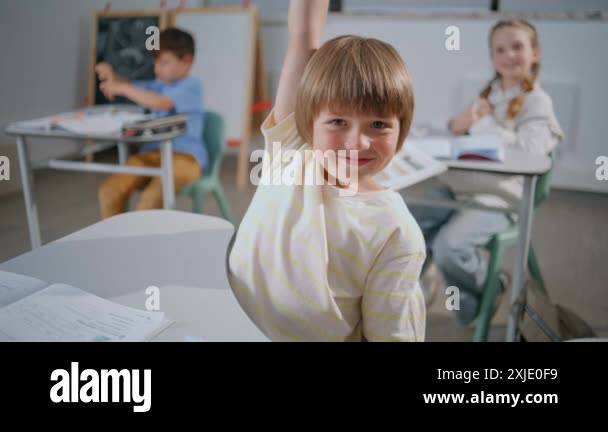 Happy boy raising hand at lesson closeup. Smiling pupil listening ...