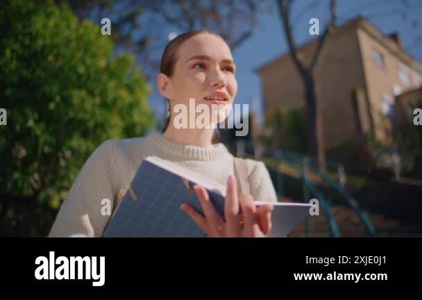 Attractive young girl student making notes in notebook standing stairs ...