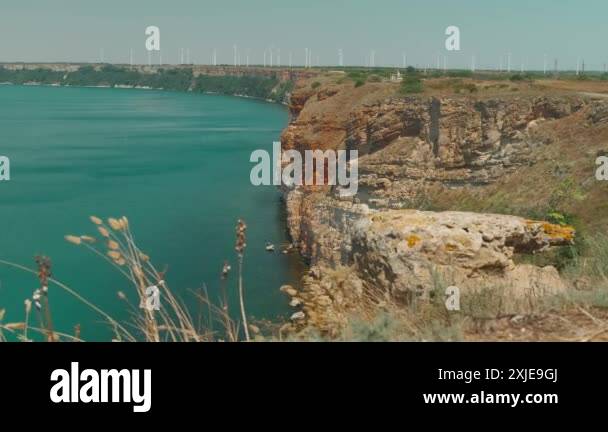 A stunning coastal cliff with wind turbines provides a breathtaking ...