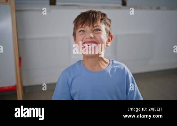 Little boy sitting school showing funny faces in classroom portrait ...