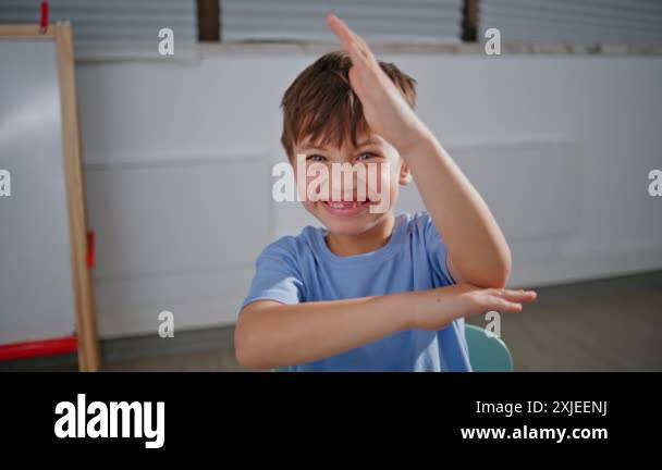 Funny child raising hand at lesson closeup. Smiling boy listening ...