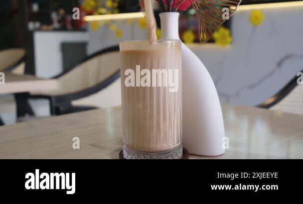 Chocolate milk pouring into a glass, splashing as it flows over ...