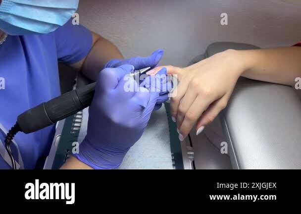 Closeup cutting cuticles on male fingers with nail drill machine in ...