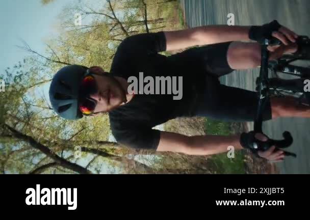 Athletic fit man cyclist is cycling on road bike in green park ...
