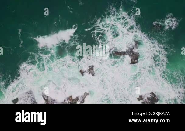 Stormy sea splashing at volcanic coastal stones top view. Dangerous ...