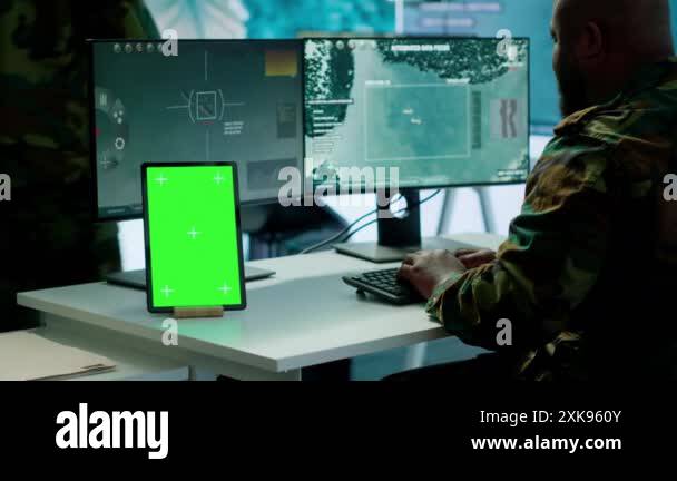 Soldier gathering real time surveillance data next to mockup display in high tech command center ...