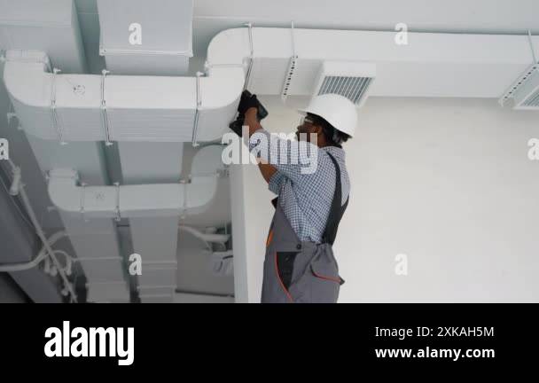 African american worker install ducted pipe system for ventilation and ...