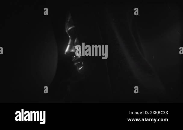 A stylised black and white sequence of a masked entity in the dark ...