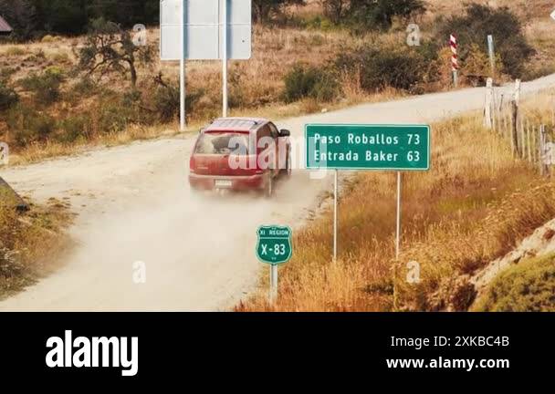 Red dirty car moves in Patagonia on unpaved dusty road and follows the ...