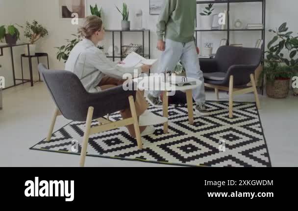 Full shot of young female sign language teacher sitting in armchair ...