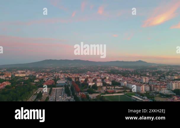 Panoramic cityscape under colorful sky with mountains at backdrop ...