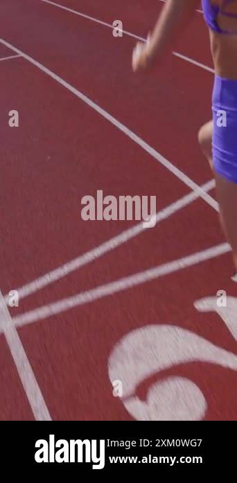 Vertical. Young woman sprinting on track at the stadium. Female athlete ...