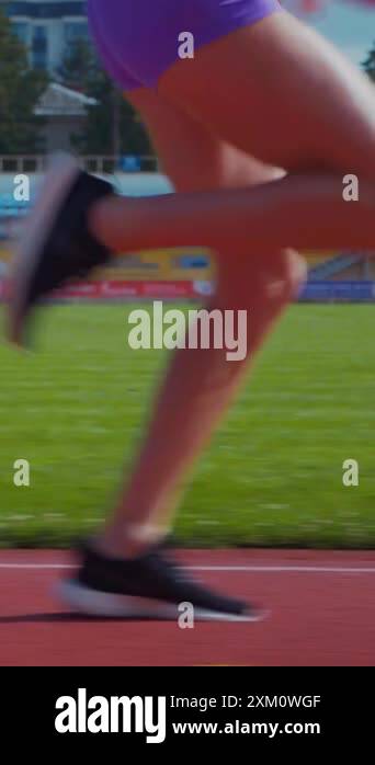 Vertical. Young woman sprinting on track at the stadium. Female athlete ...