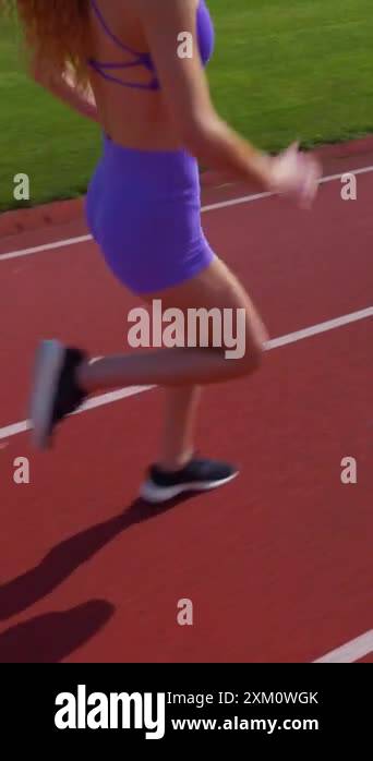 Vertical. Young woman sprinting on track at the stadium. Female athlete ...