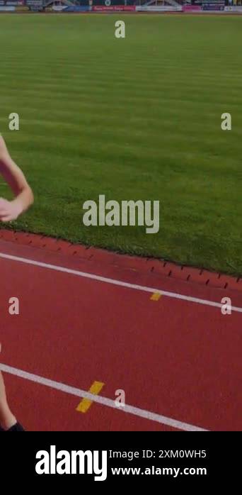 Vertical. Young woman sprinting on track at the stadium. Female athlete ...