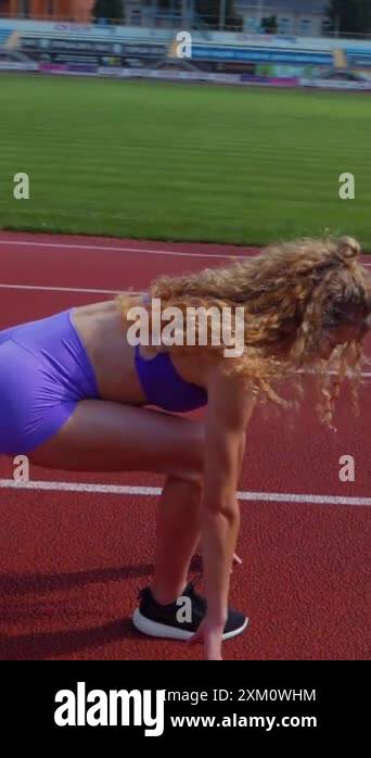 Vertical. Young woman sprinting on track at the stadium. Female athlete ...