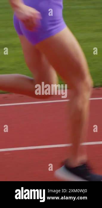Vertical. Young woman sprinting on track at the stadium. Female athlete ...