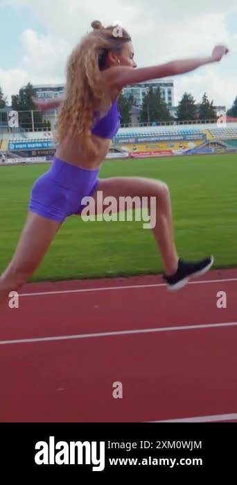 Vertical. Young woman sprinting on track at the stadium. Female athlete ...