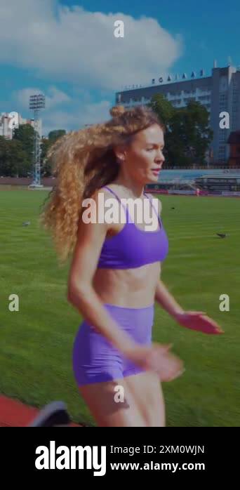 Vertical. Young woman sprinting on track at the stadium. Female athlete ...