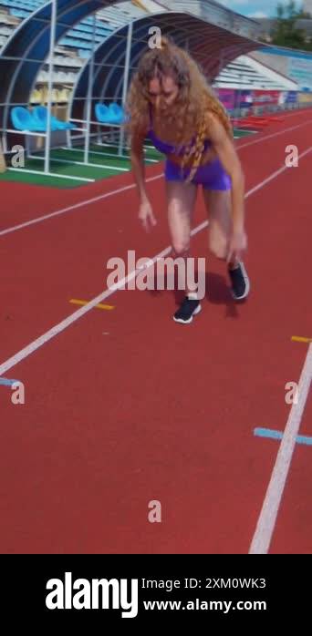 Vertical. Young woman sprinting on track at the stadium. Female athlete ...