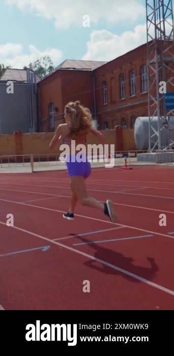Vertical. Young woman sprinting on track at the stadium. Female athlete ...