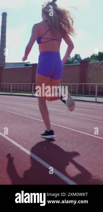 Vertical. Young woman sprinting on track at the stadium. Female athlete ...