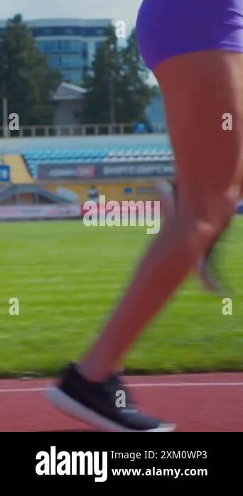 Vertical. Young woman sprinting on track at the stadium. Female athlete ...