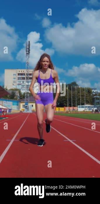 Vertical. Young woman sprinting on track at the stadium. Female athlete ...