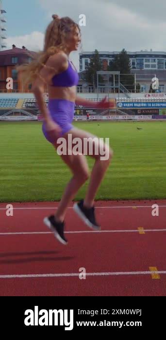 Vertical. Young woman sprinting on track at the stadium. Female athlete ...