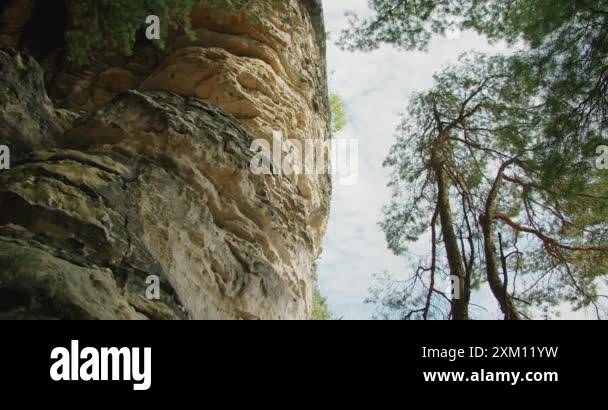 Rocky cliffside with trees and a sandy trail winding through a forest ...