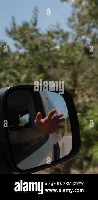 Vertical video. A Hand Reaching Out the Window of a Car, Feeling the ...