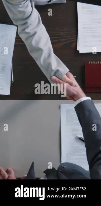 Vertical top down close-up shot of handshake of unrecognisable co ...
